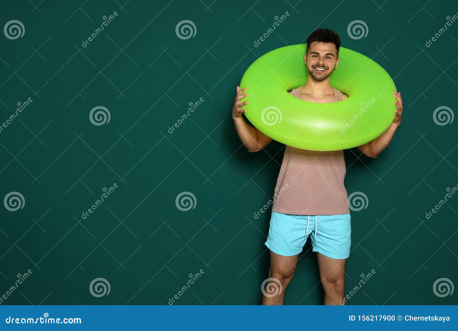 Funny Young Man with Bright Inflatable Ring on Green Background, Space ...