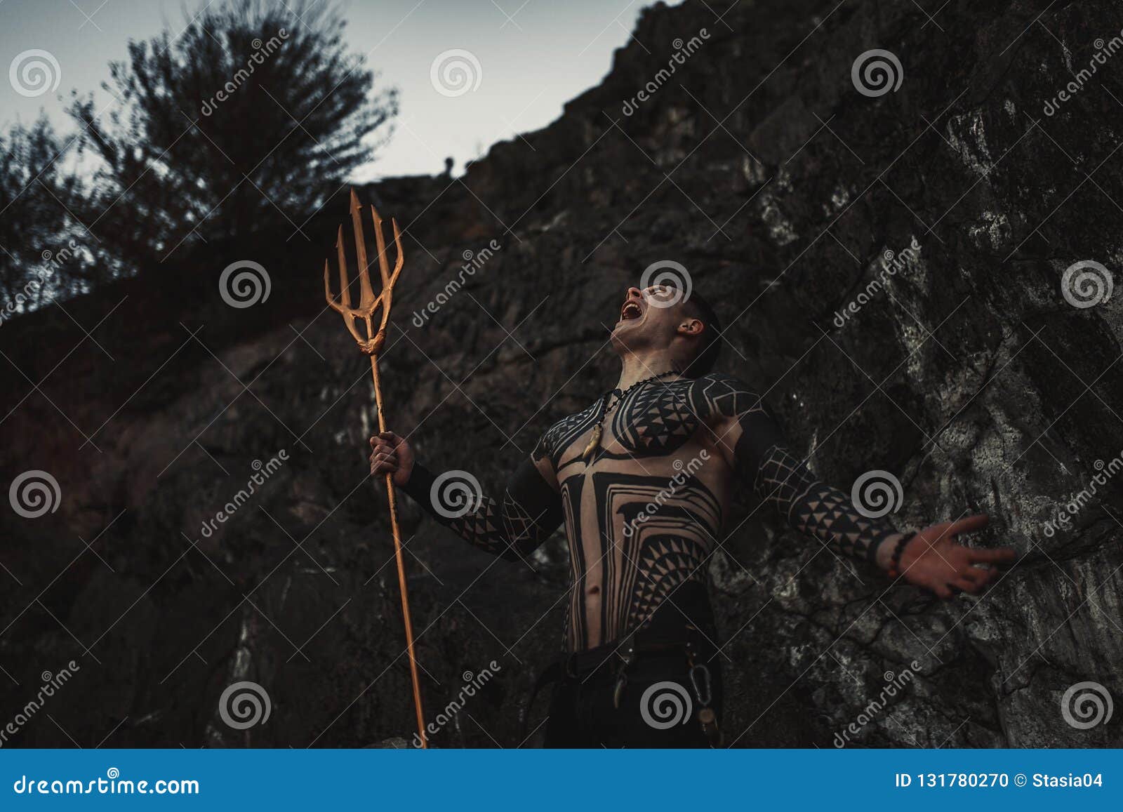 A Fury Man with a Trident in His Hands Against the Background of Rocks ...