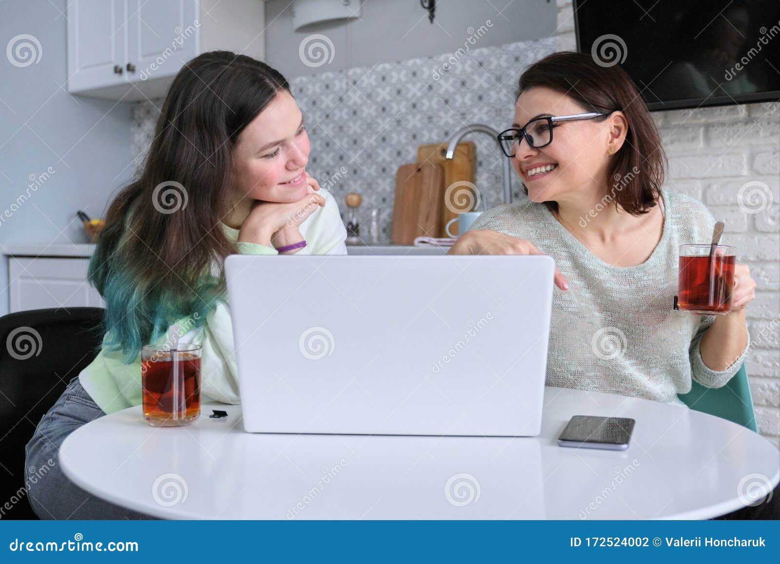 Föräldrar Och Tonåringar Som Sitter Hemma I Köket Och Tittar På Skärmen