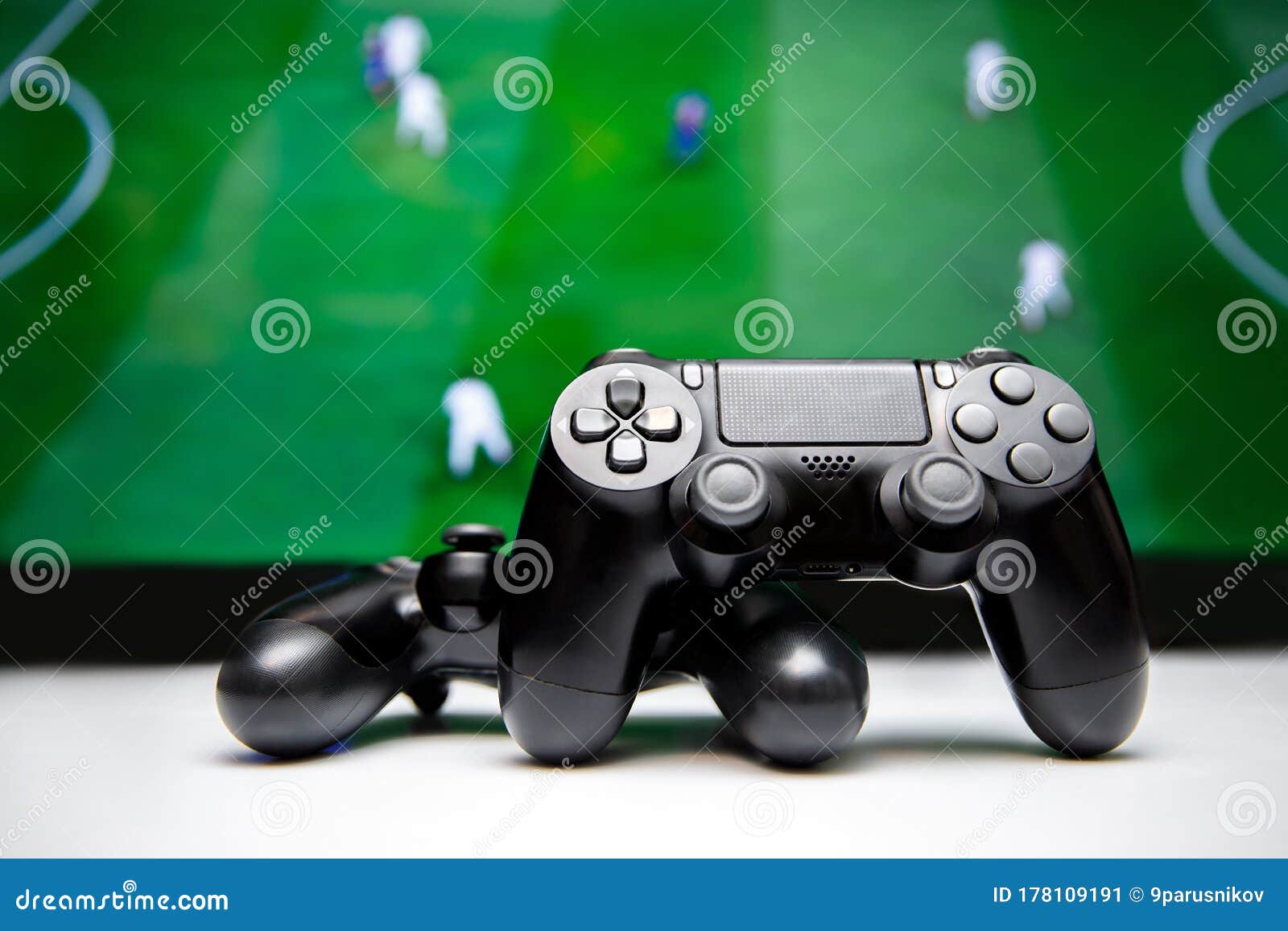 Game Controller for Consoles on a White Table. a Football Game on ...