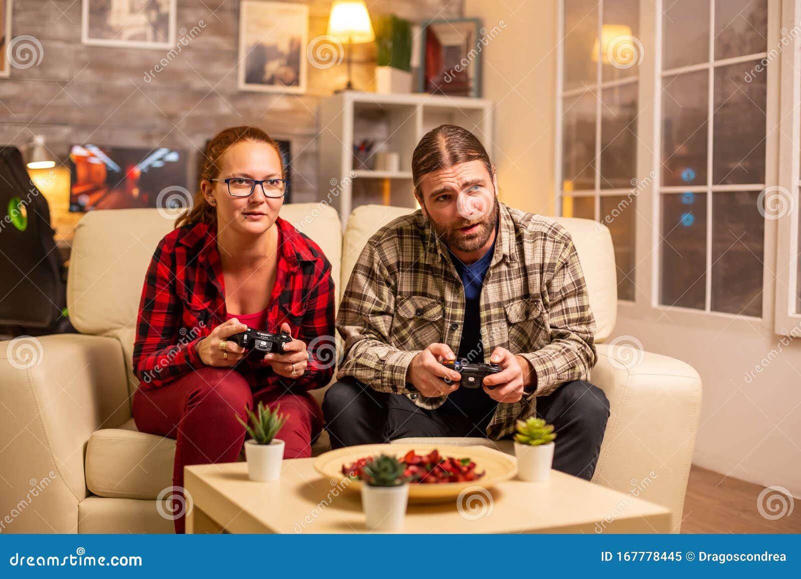 Gamers Couple Playing Video Games on the TV with Wireless Controllers ...