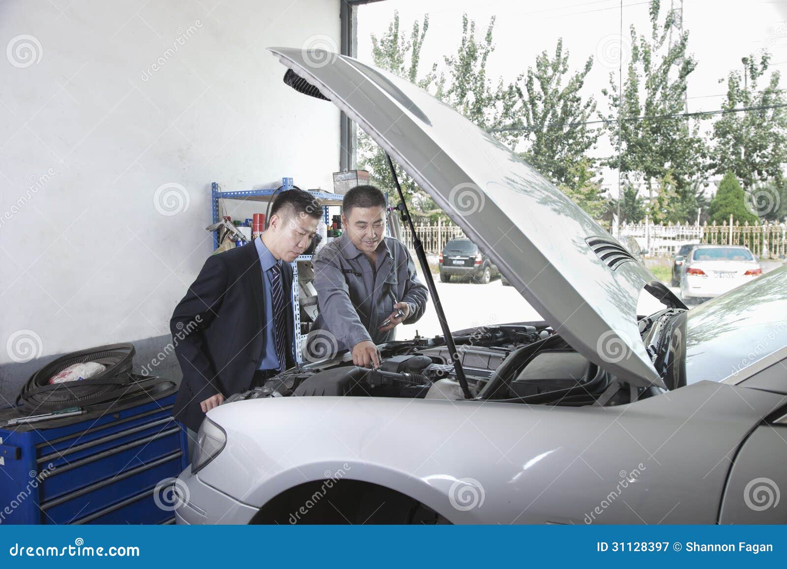 Garage Mechanic Explaining To Customer and Looking at Car with Open ...