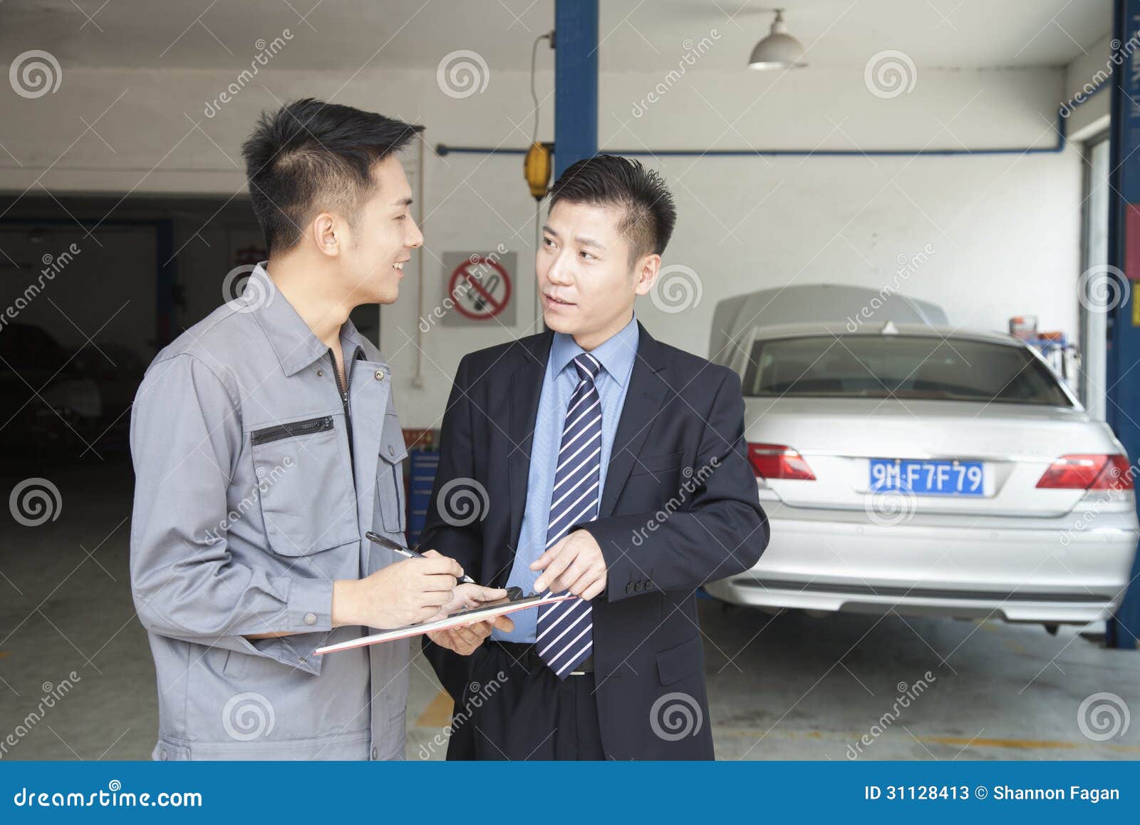 Garage Mechanic Explaining To Customer, Showing Him the Bill Stock ...