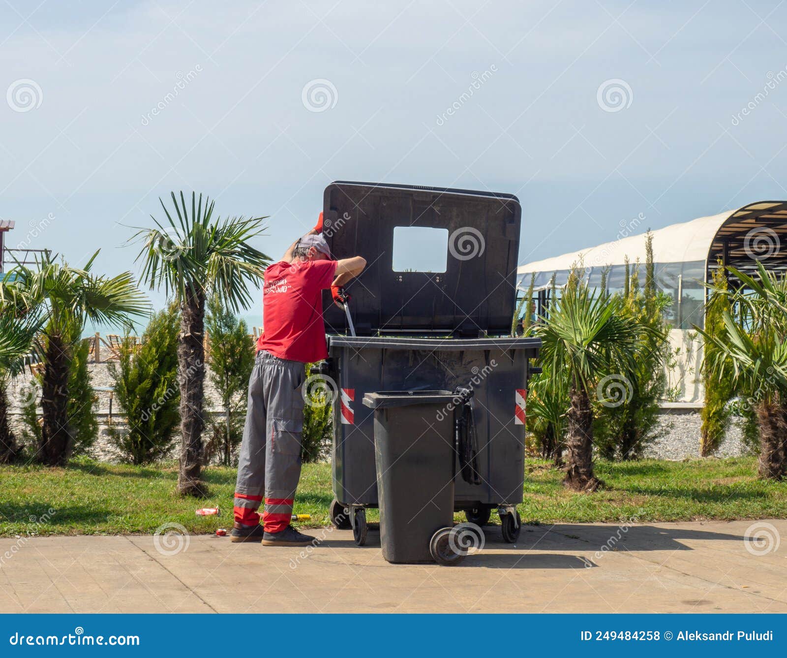 The Garbage Man Puts the Garbage in a Large Garbage Container. Man at ...