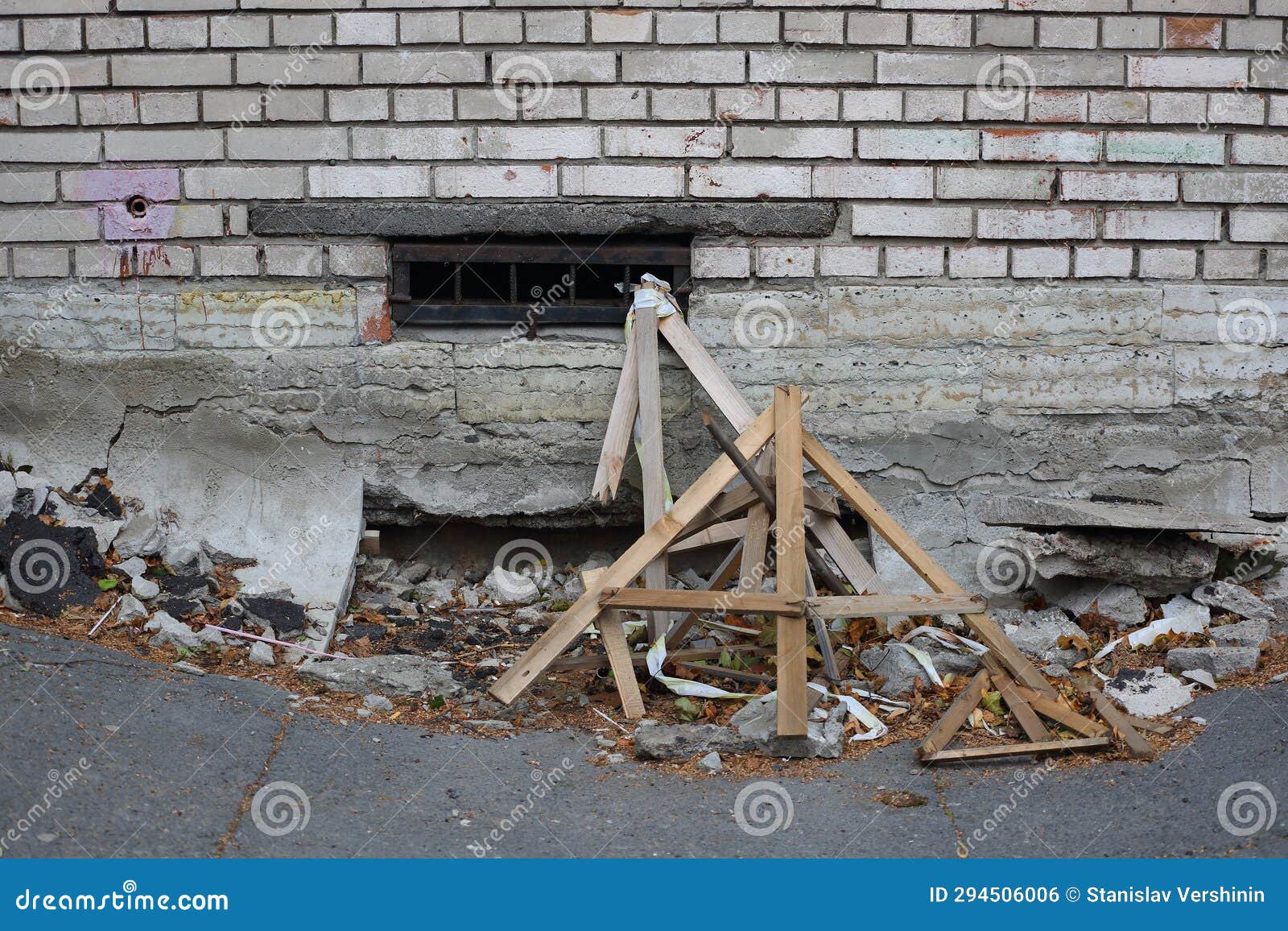 Garbage is Piled Near a Narrow Barred Basement Window in a White Brick ...