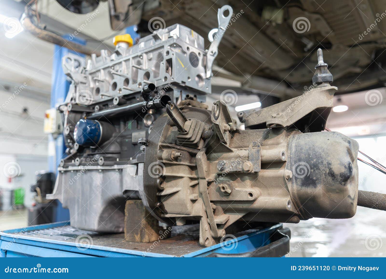 A Gearbox Mounted on a Car Engine Stands on a Workbench, Under the Car ...