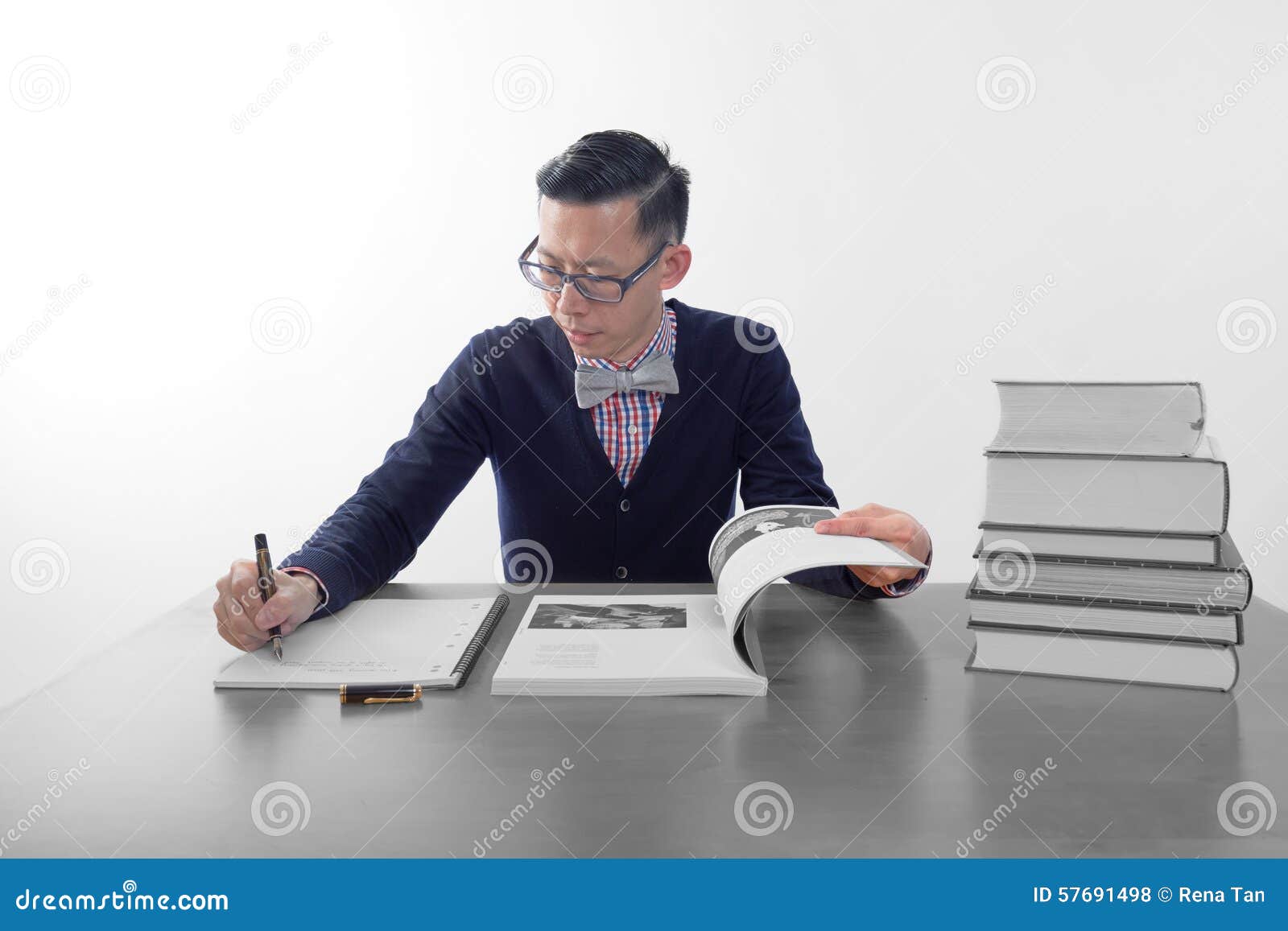 Geek Chic: Man Writing on Notepad, with Open Book and Stack of Books on ...