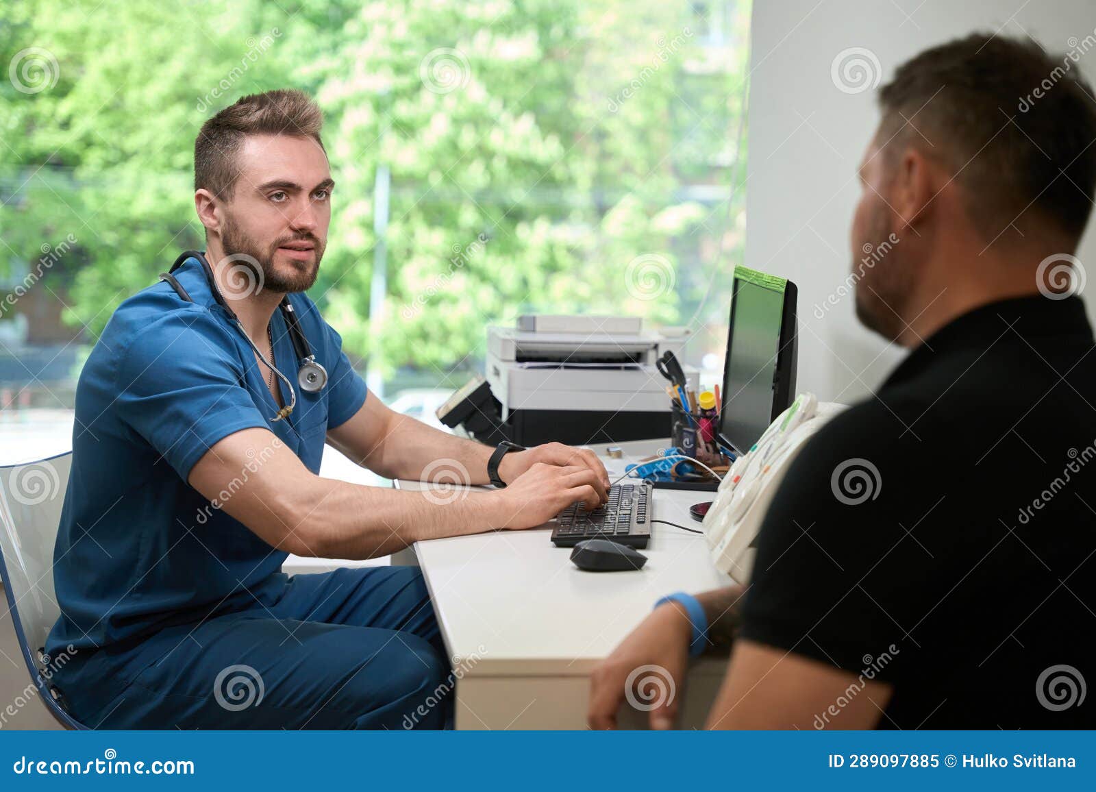 General Practitioner Entering Patient Information into His Desktop ...