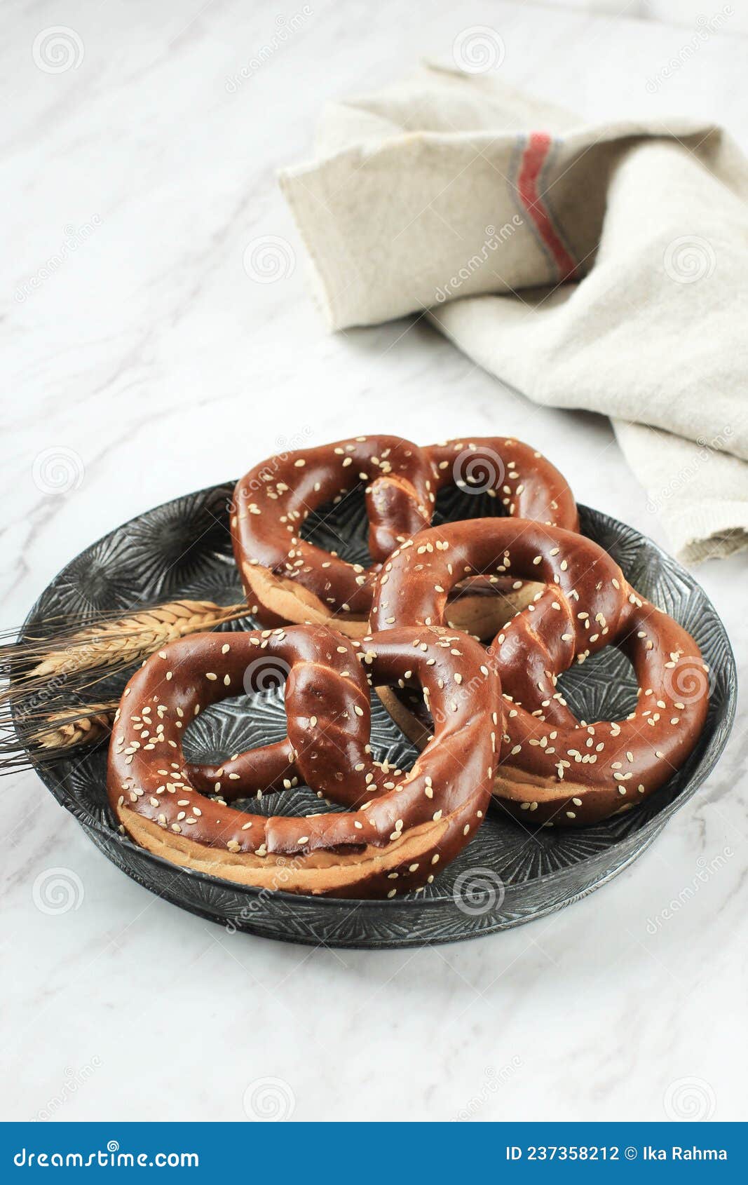 German Brezel Pretzel with Sesame Seed on Rustic Plate Stock Photo ...