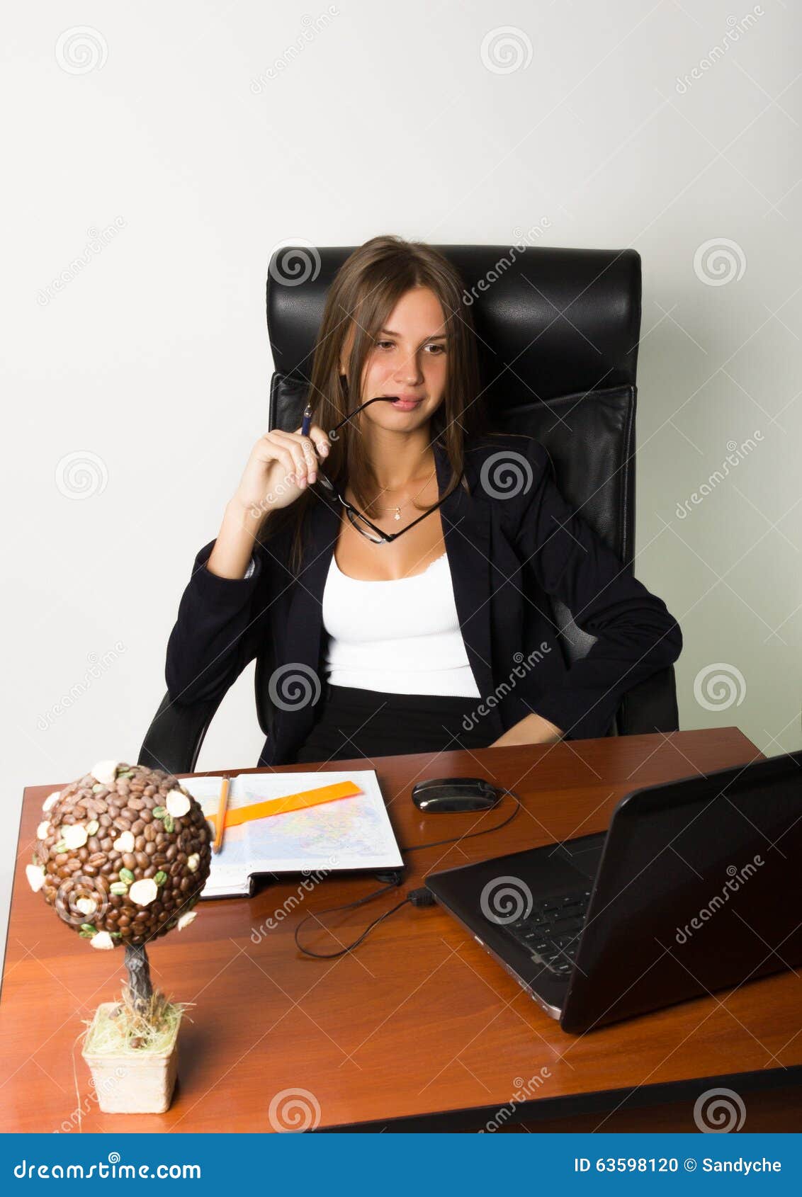 Geschäftsfrau In Einer Klage Die An Einem Schreibtisch Sitzt Stockfoto