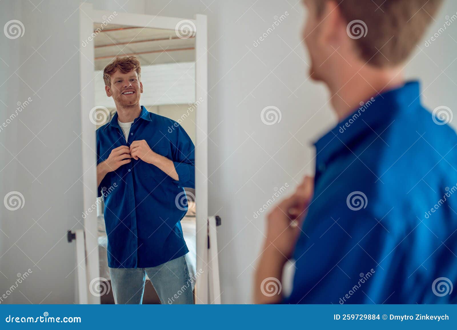 A Confident Young Man Getting Dressed at the Mirror Stock Photo - Image ...