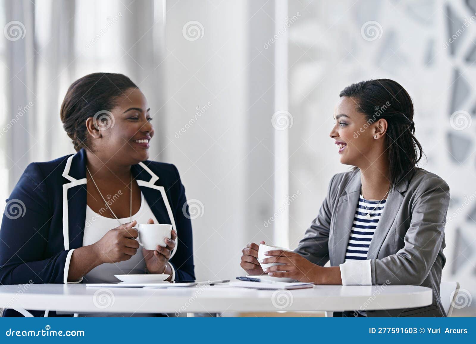 Getting Work Done with a Smile. Two Coworkers Talking Together while ...