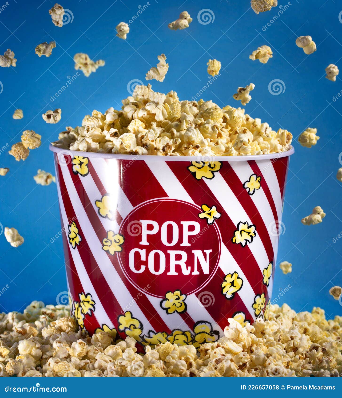 A Giant Bucket of Falling Butter Popcorn on a Blue Background Stock ...
