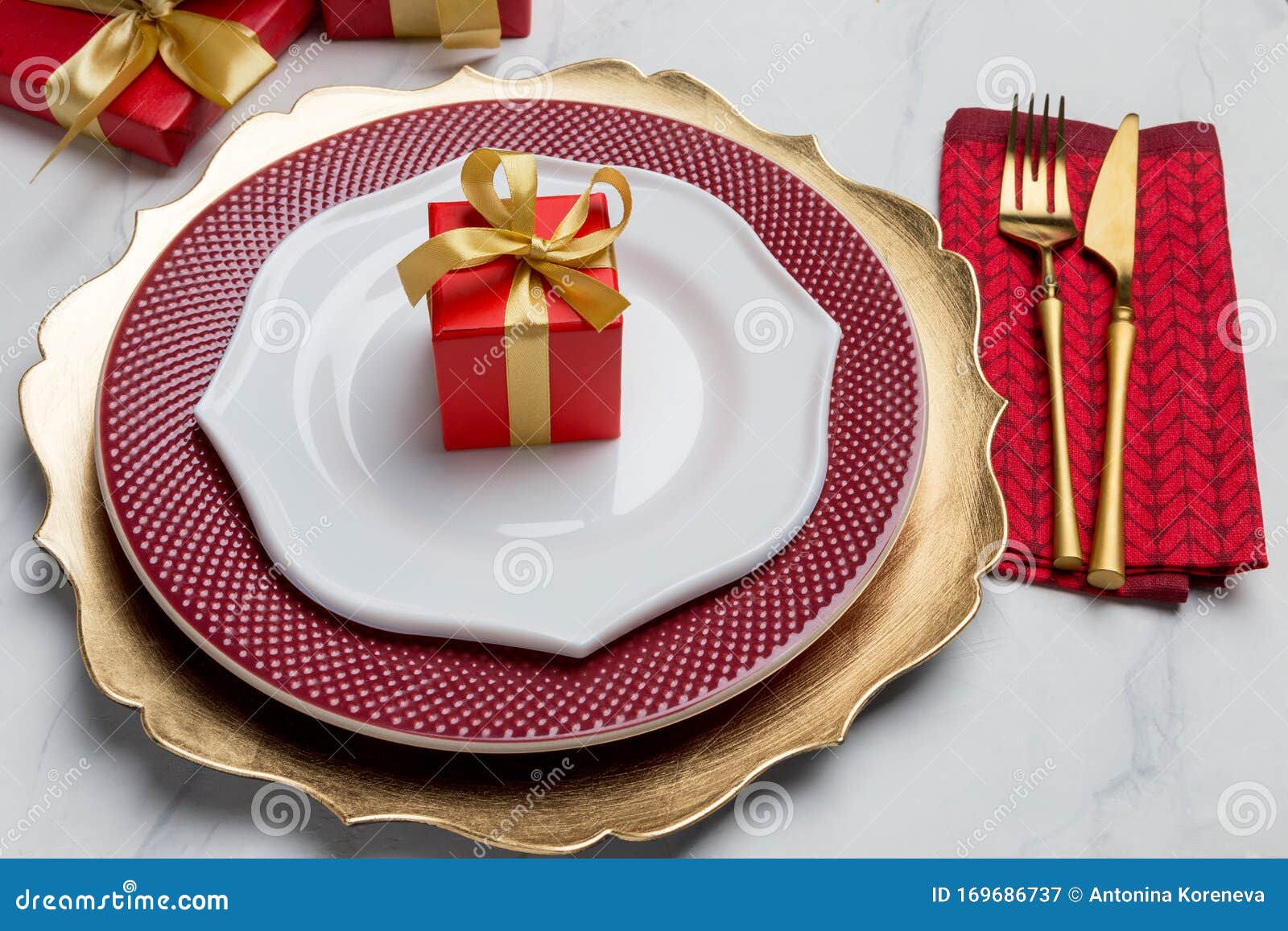 Gift Box on Empty Plate with Table Setting and Golden Tableware Stock ...