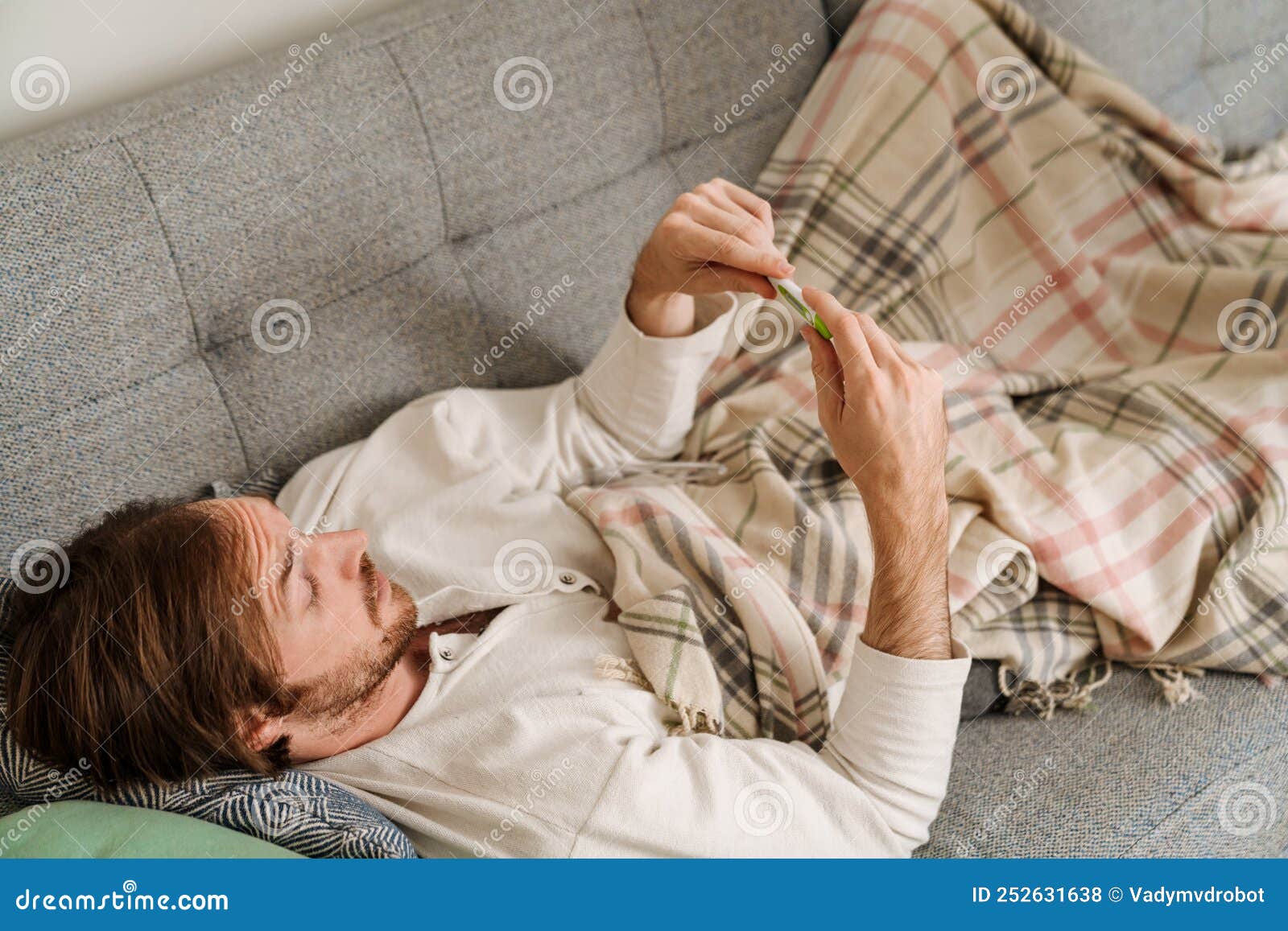 Ginger Man Feeling Sick and Measuring Temperature while Lying on Couch ...