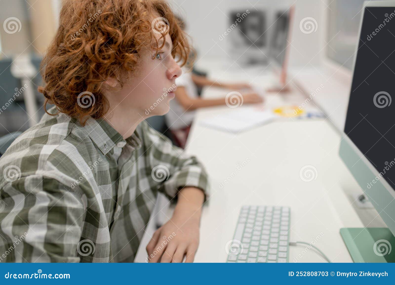A Ginger Schoolboy Sitting at the Computer at School and Looking ...