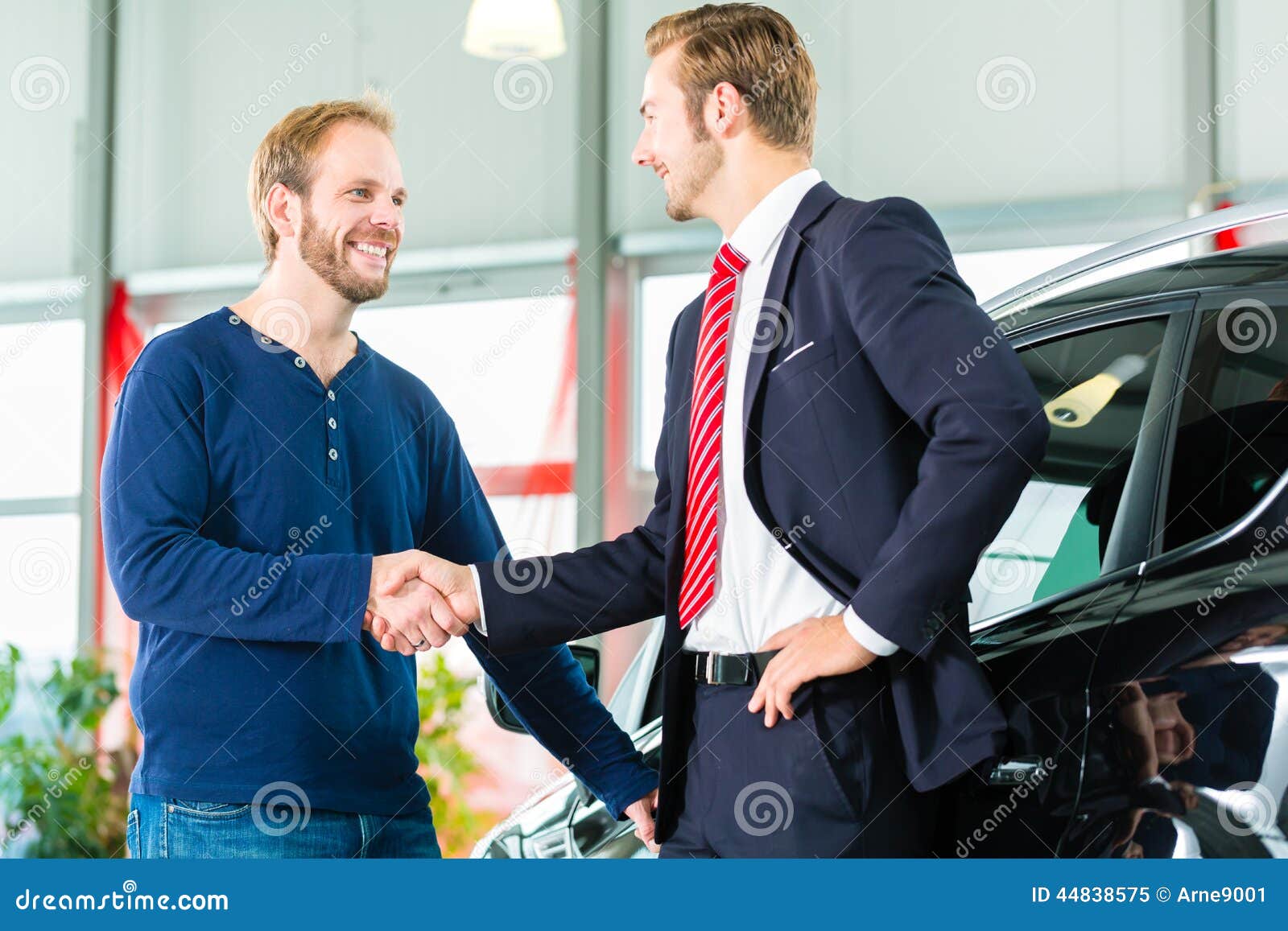 Giovane E Venditore Con L'auto Nel Concessionario Auto Immagine Stock ...