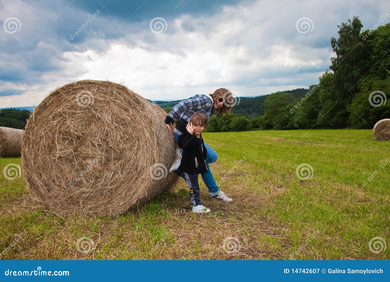 A Girl and a Boy Pushing a Round Bundle of Straw. Stock Image - Image ...