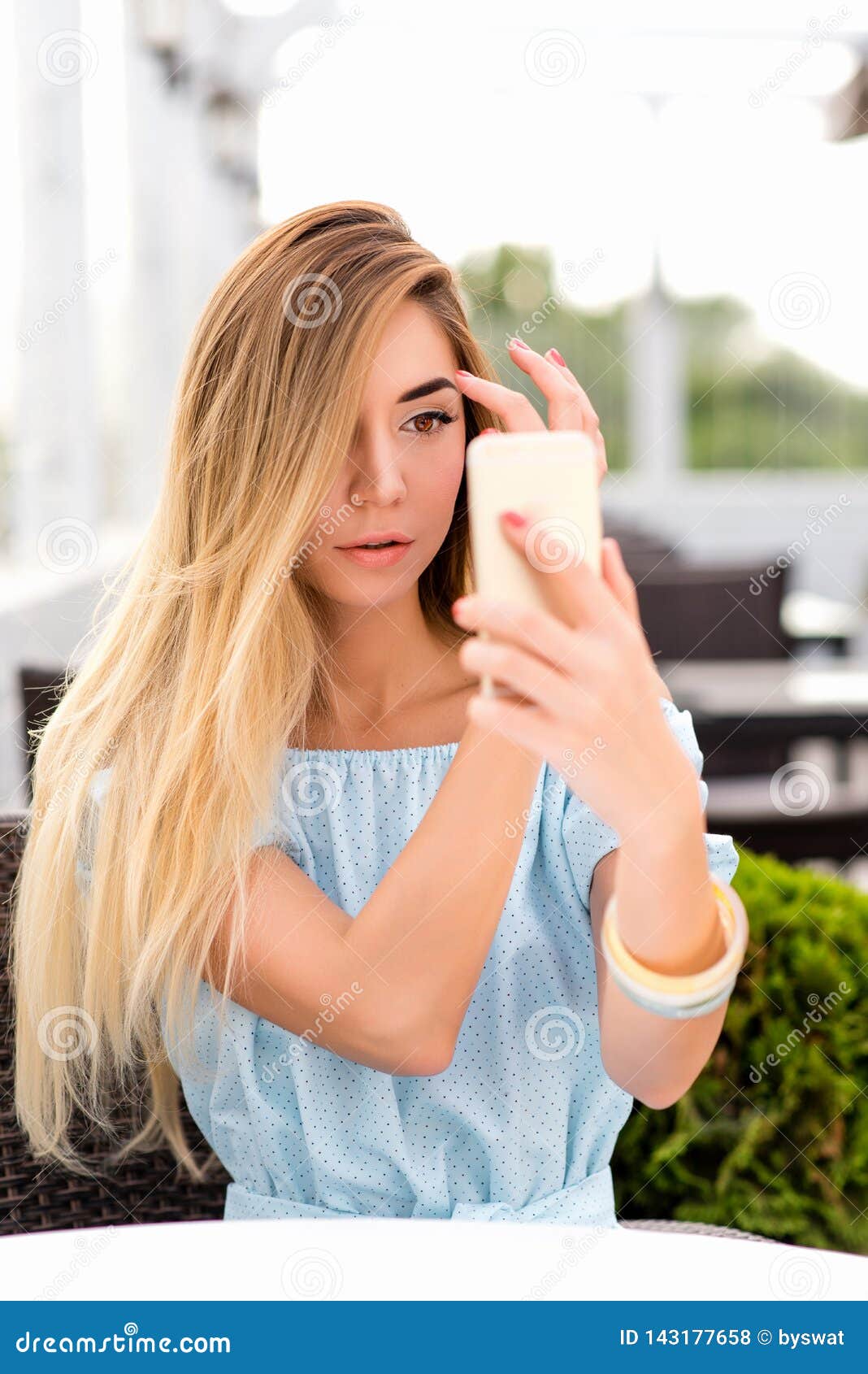 A Girl In A Cafe Adjusts Her Hair Long Hair In Her Hand A Mobile Phone