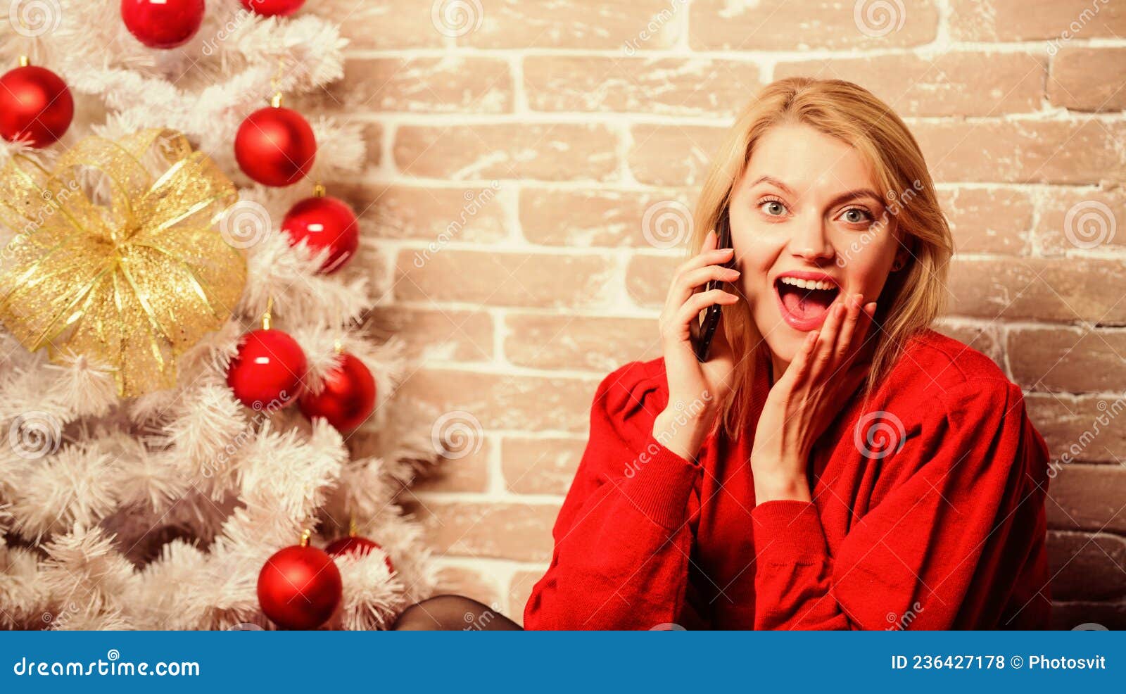 Girl In Dress Sit Near Christmas Tree With Ornaments Waiting For