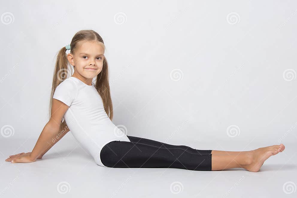 Girl Gymnast Sitting On The Floor With Legs Stretched And Leaned Back