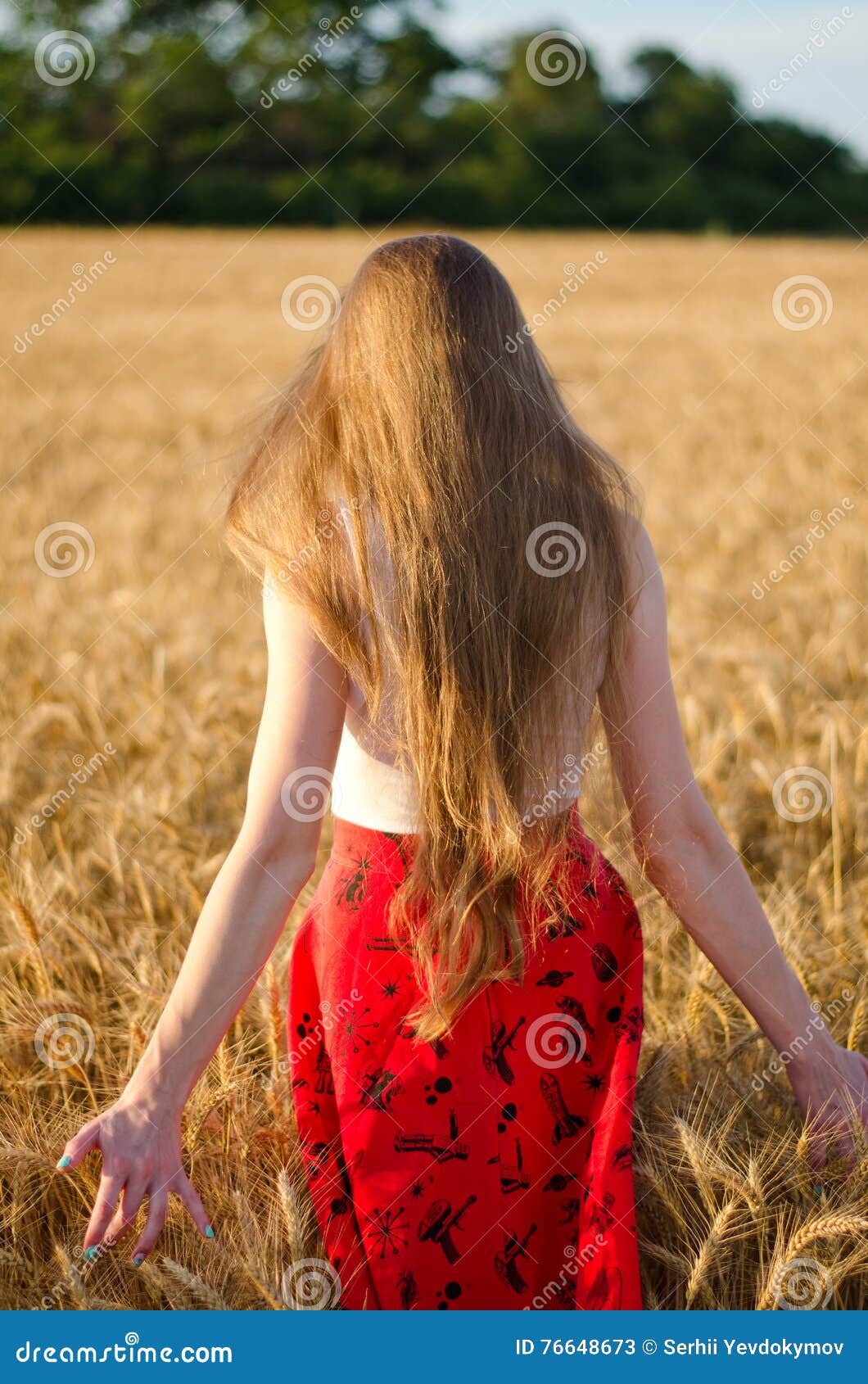 Girl With Long Hair Standing In A Wheat Field With His Back In The