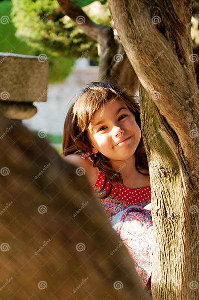 Girl Peeking Around Tree stock image. Image of smiling - 17792631