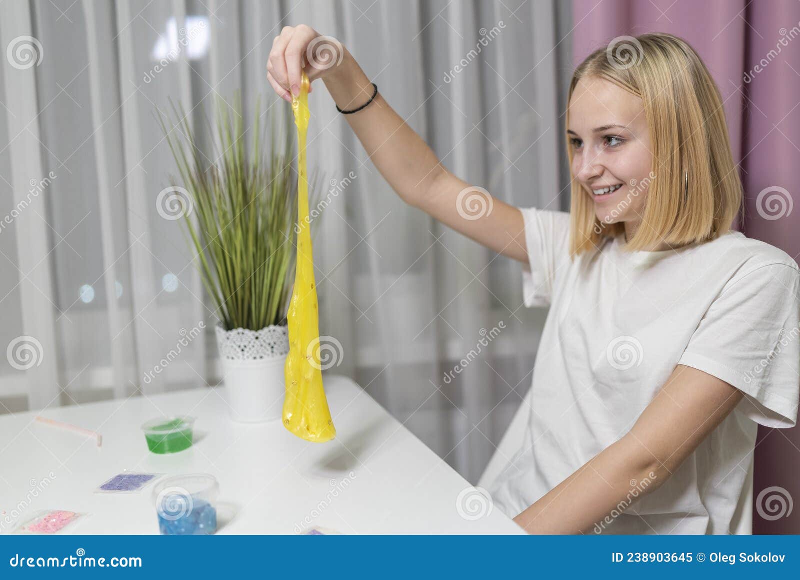 Girl Playing with Yellow Shiny Slime at the Table at Home Stock Image ...