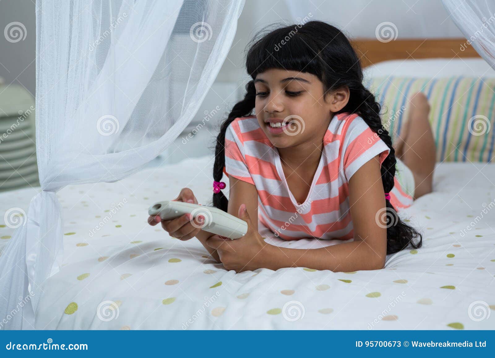 Girl Pressing Remote Control while Lying on Bed Stock Image - Image of ...