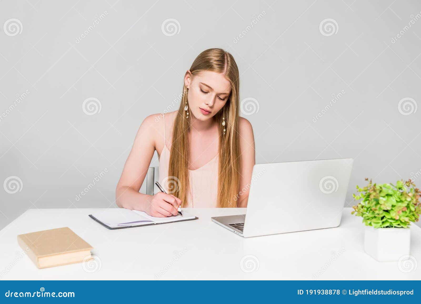Girl Sitting at Computer Desk and Writing in Notebook on Grey Stock ...