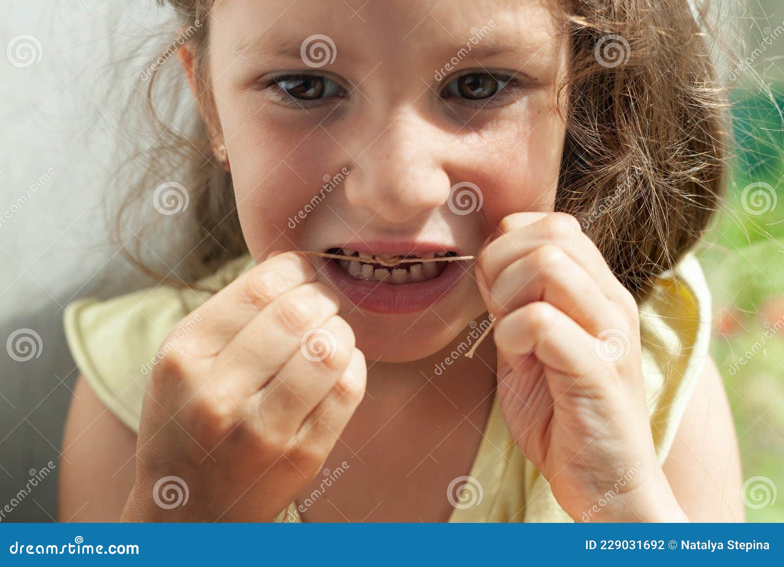 A Girl of Six Years Tied a Thread on a Tooth and Tries To Pull Out a ...