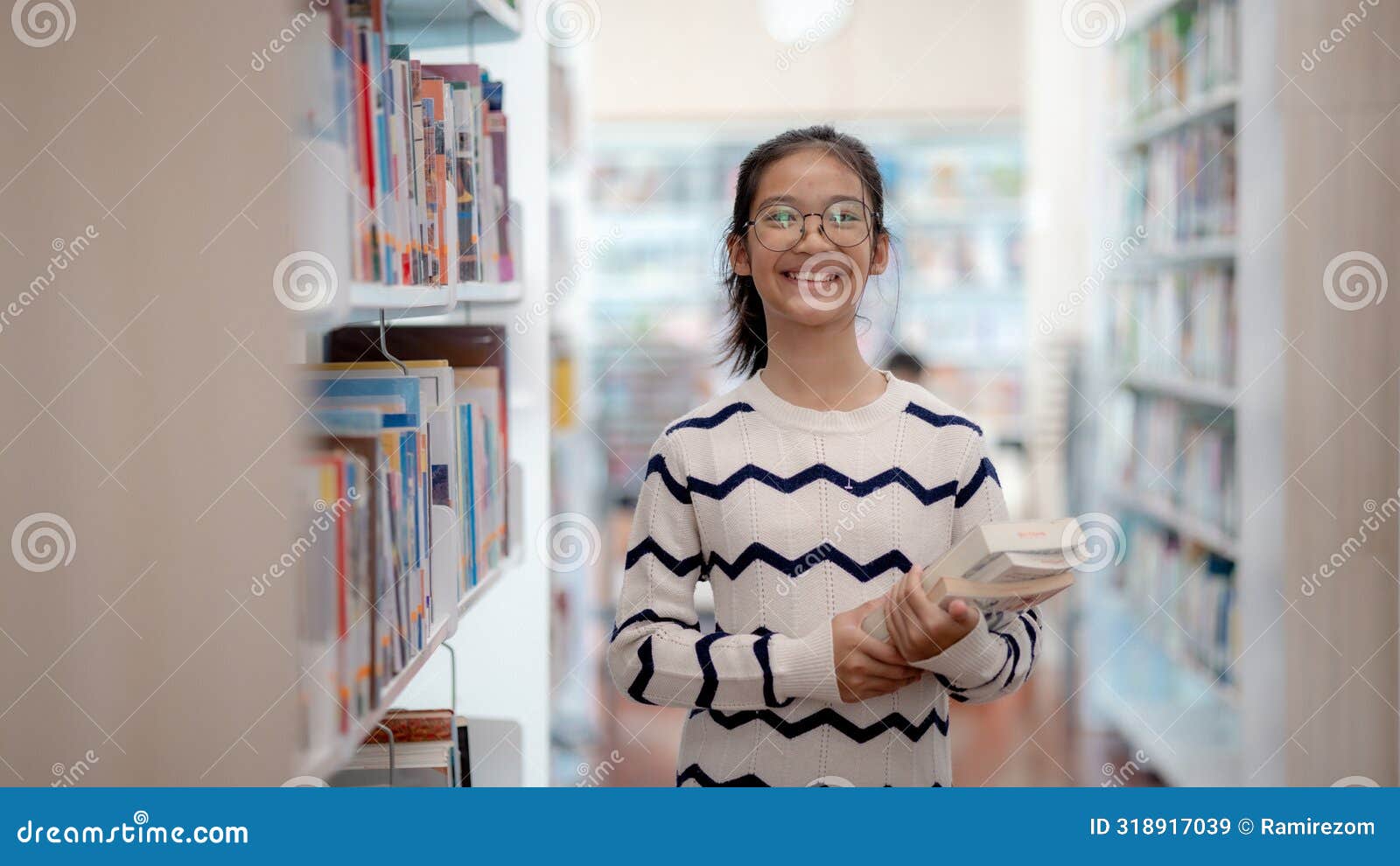 A Girl is Smiling and Holding a Stack of Books in a Library Stock Image ...