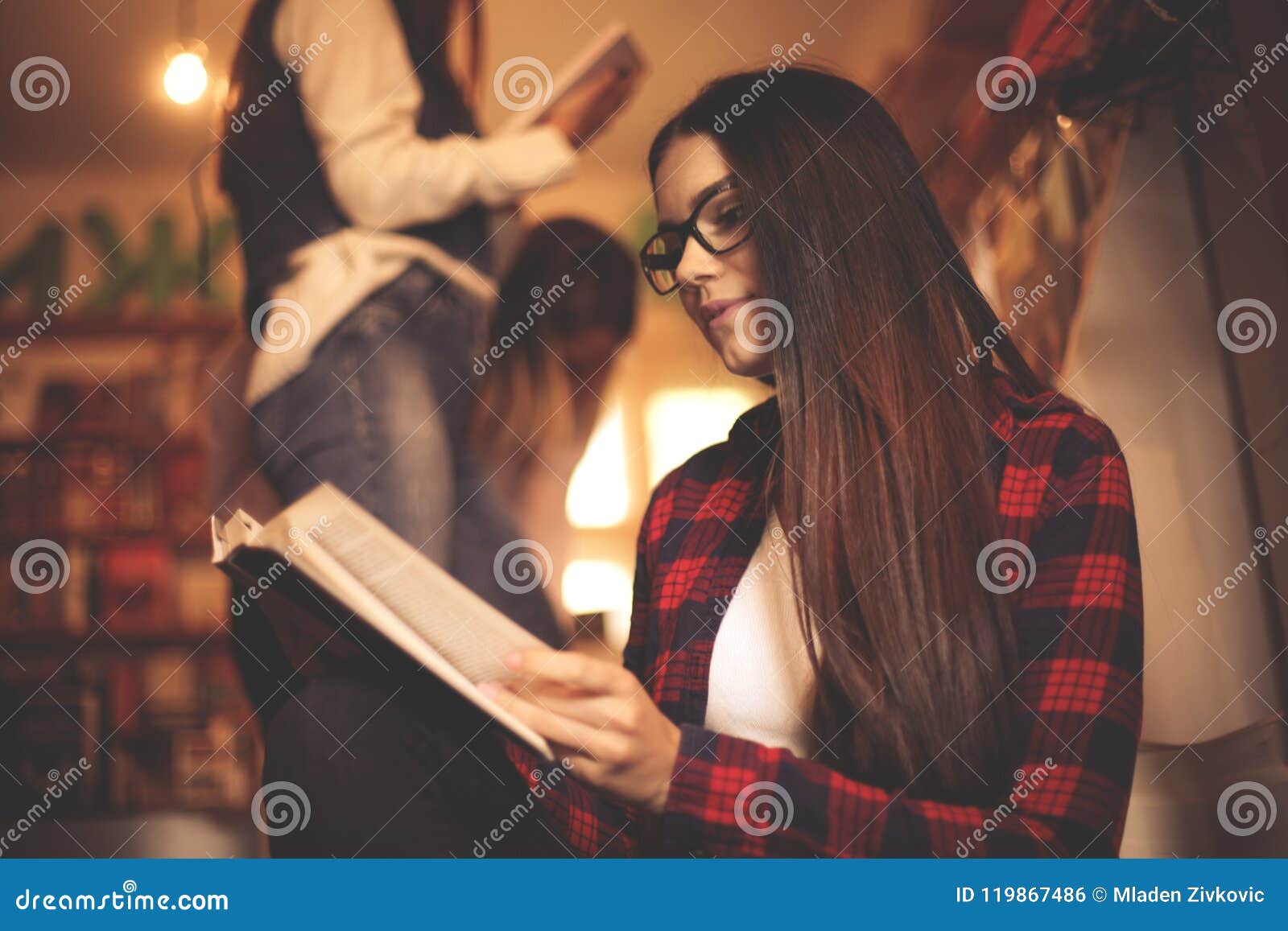 Girl Student Sitting Down in Library and Reading Book. Stock Photo ...
