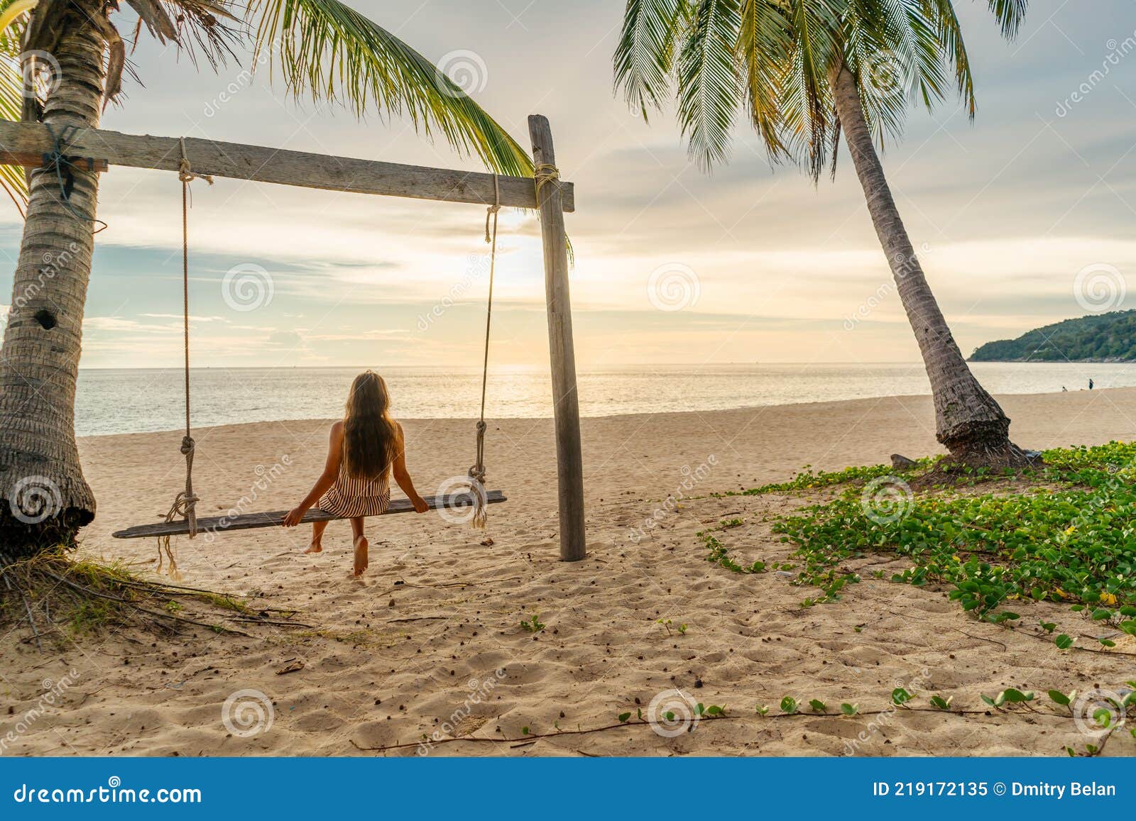 The Girl Swings On The Swing And Looks At The Sunset On The Tropical