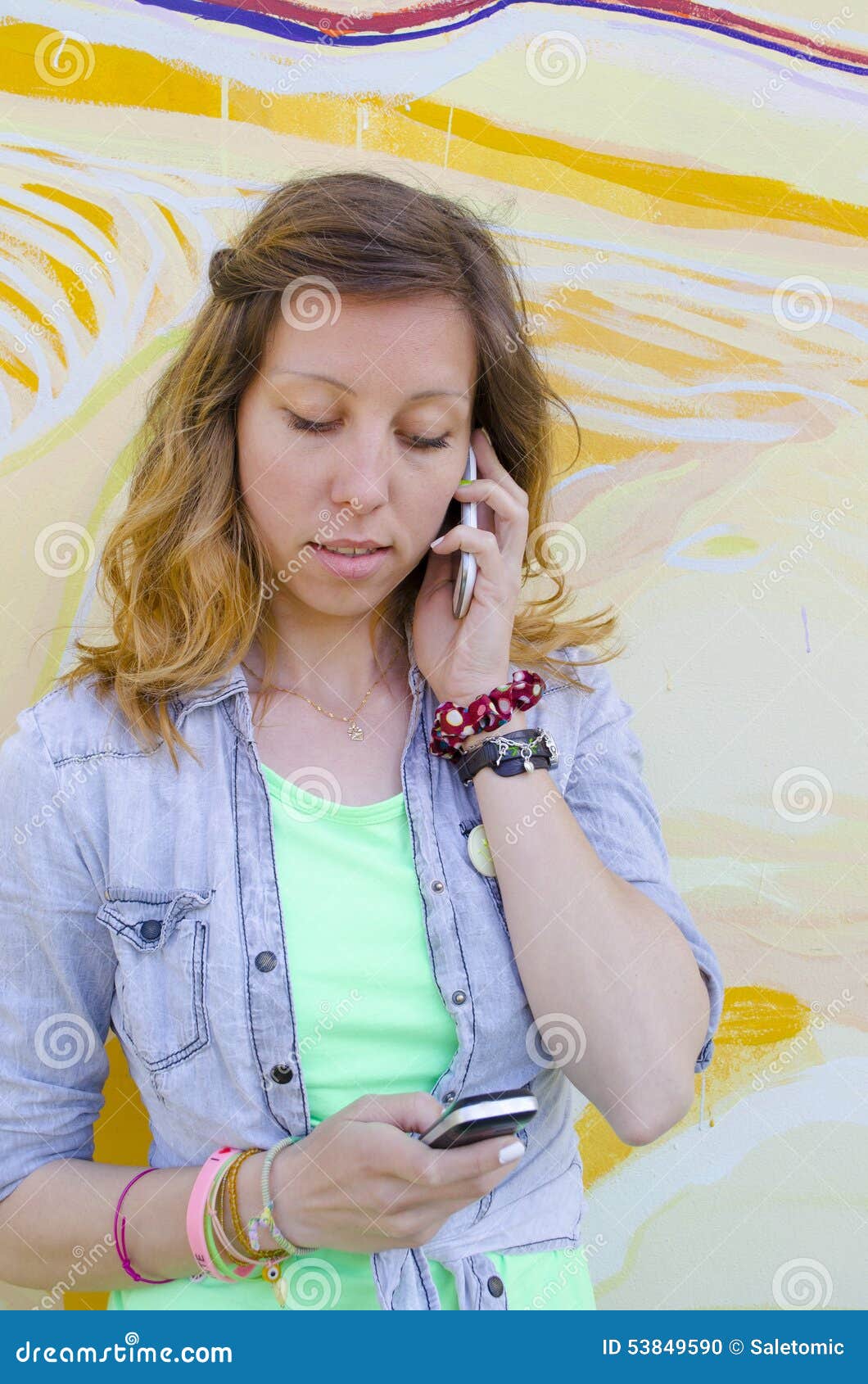 Girl Talking on One Phone while Reading a Text Message Stock Photo ...