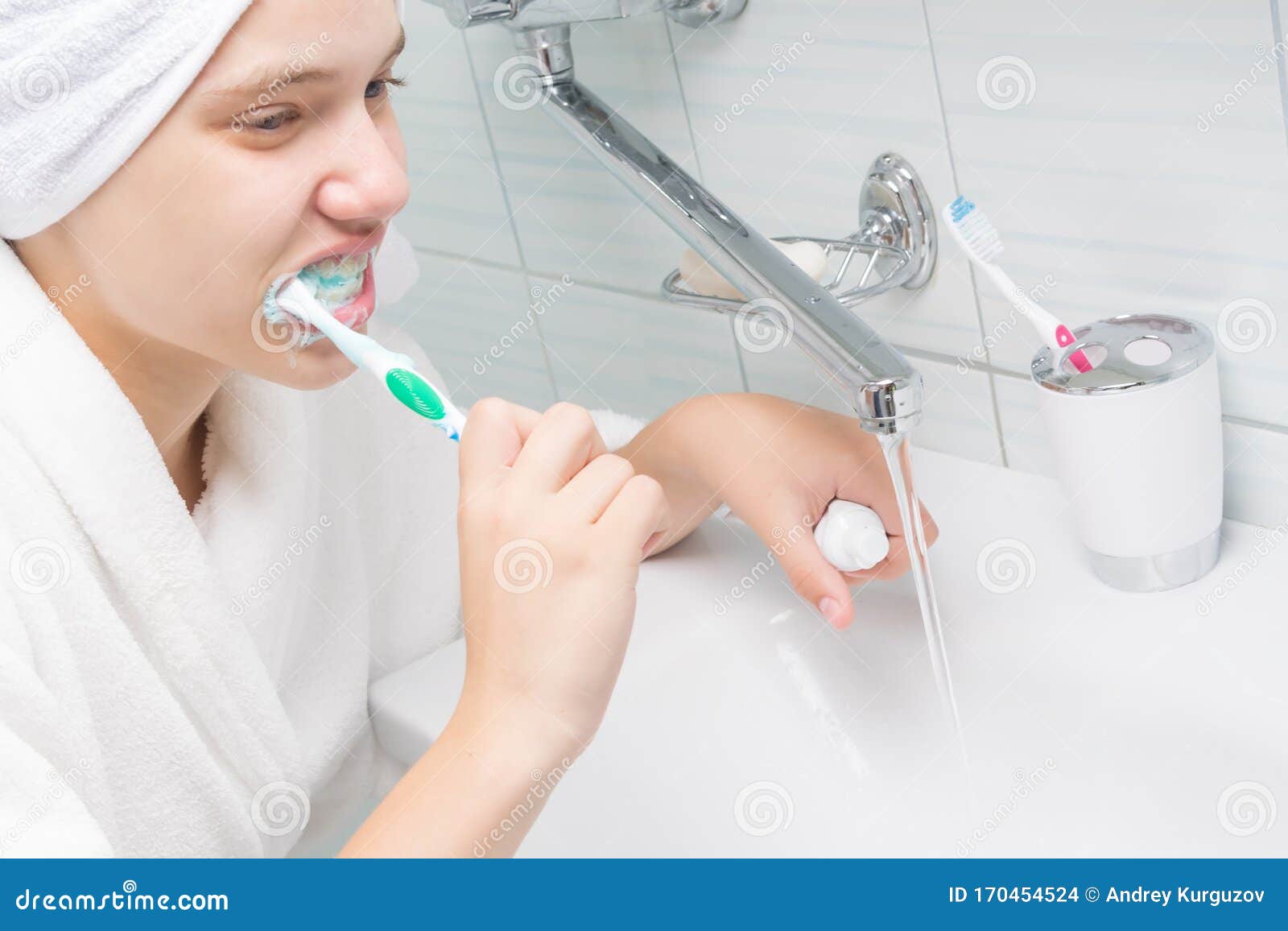 Girl Using a Brush with Toothpaste Brushes Teeth in the Bathroom Stock ...