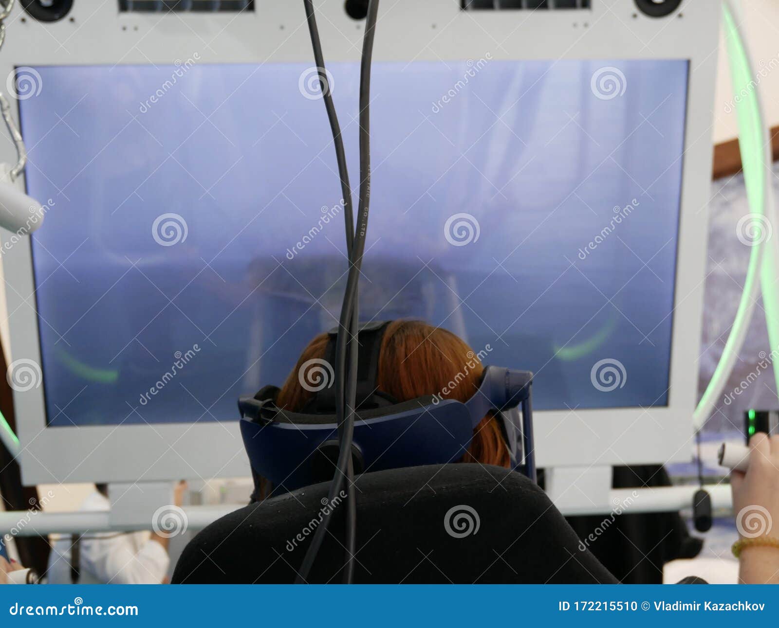 A Girl on a Virtual Hang Glider Ride Sits in a Virtual Reality Helmet ...
