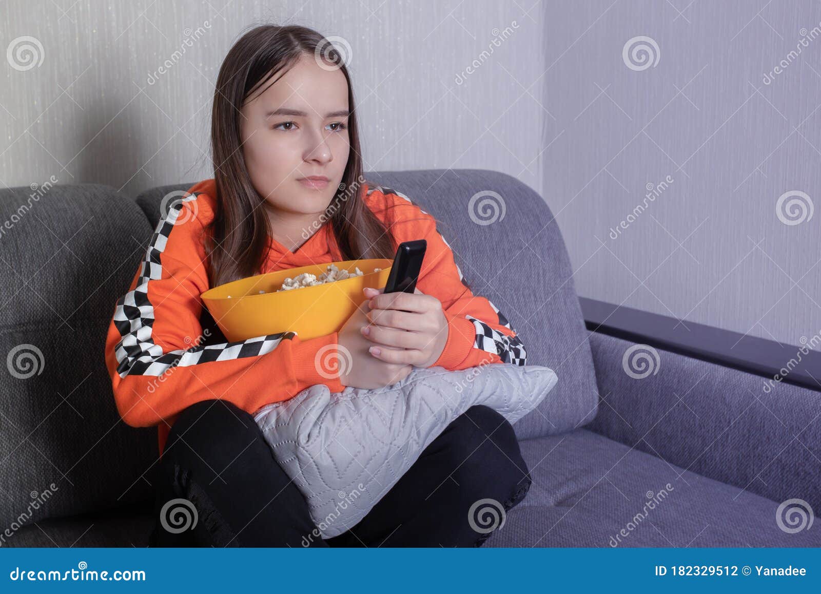 Girl Watching The News Sitting With The Remote Control On The Couch