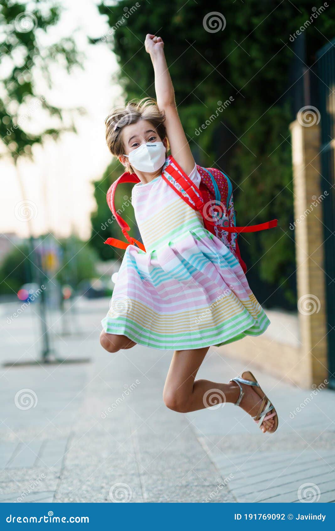Girl Wearing a Mask Takes a Jump for Joy at Going Back To School. Stock ... Girl Wearing a Mask Takes a Jump for Joy at Going Back To School. Stock ...