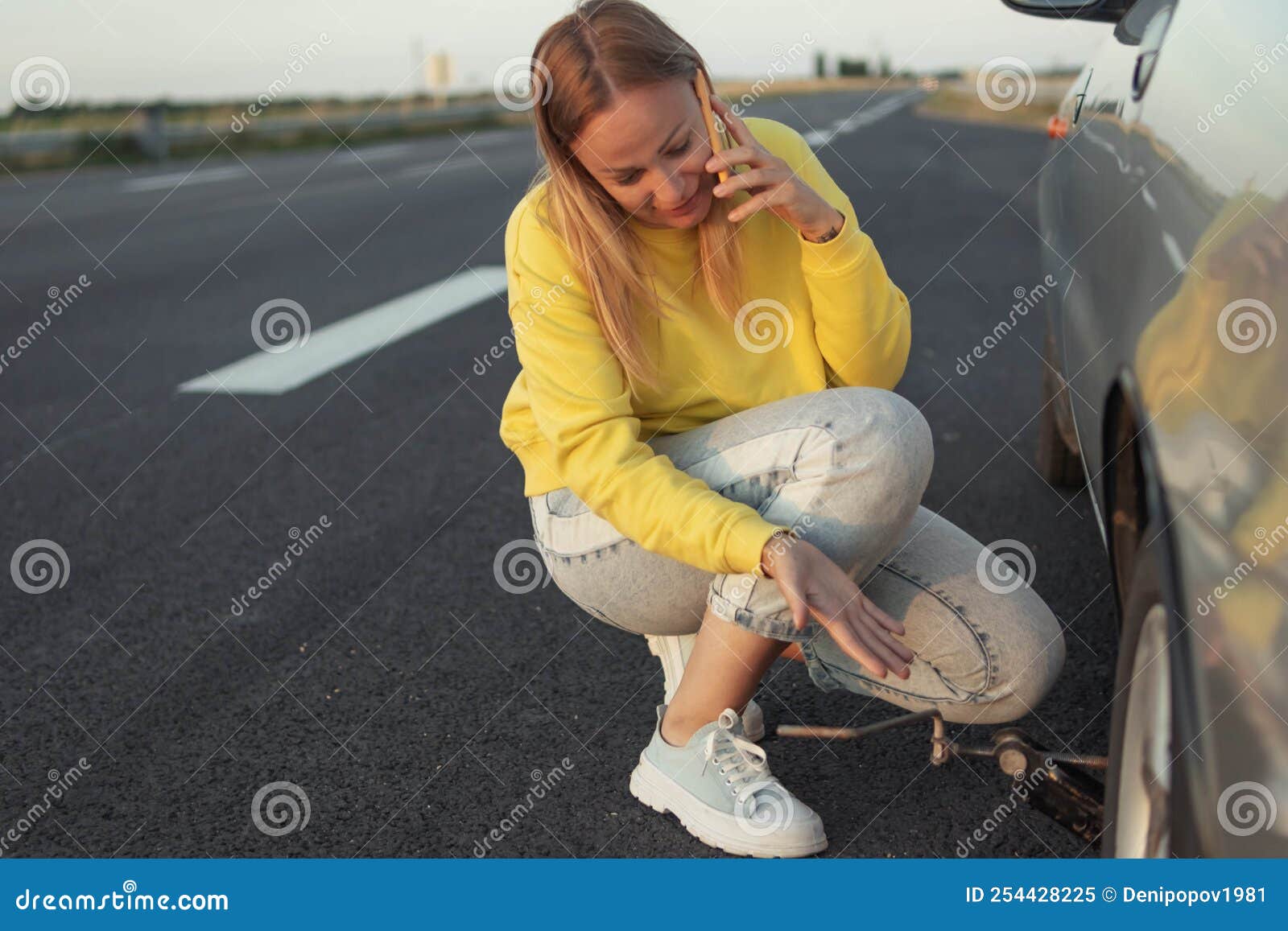 A Girl In A Yellow Sweater And Jeans Of European Appearance Sits Near