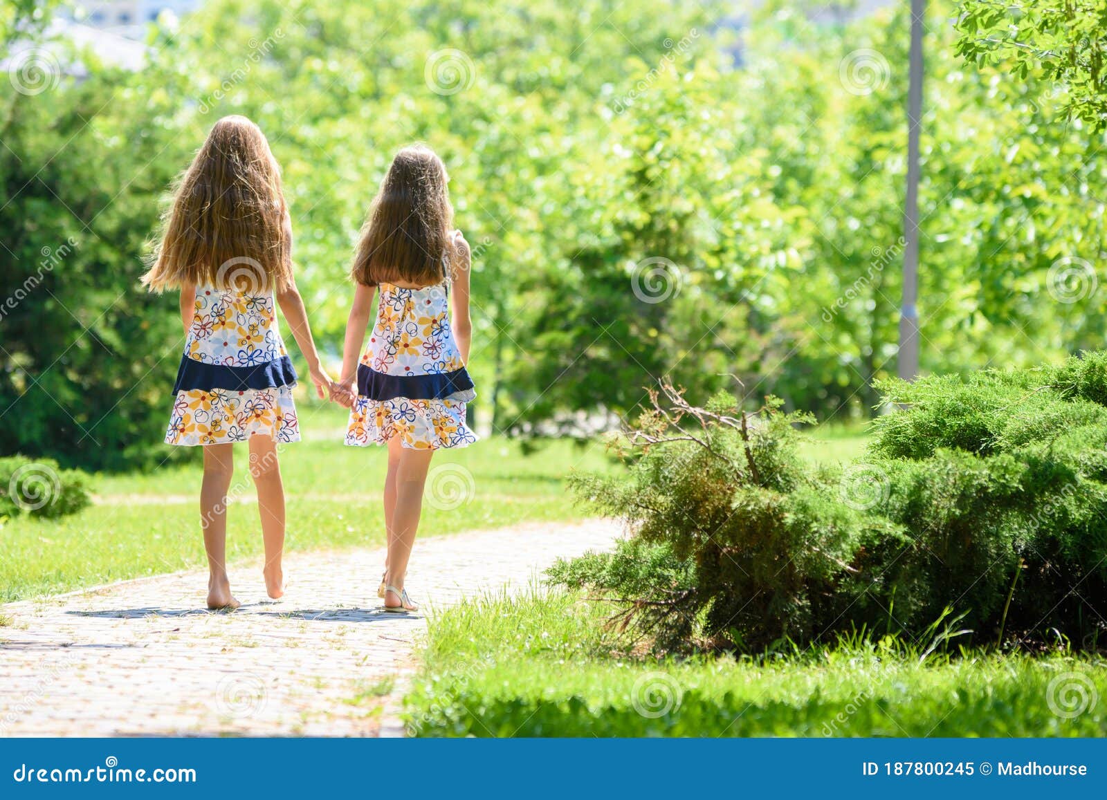Girlfriends in Identical Clothes Go by the Handle in a City Park Stock ...