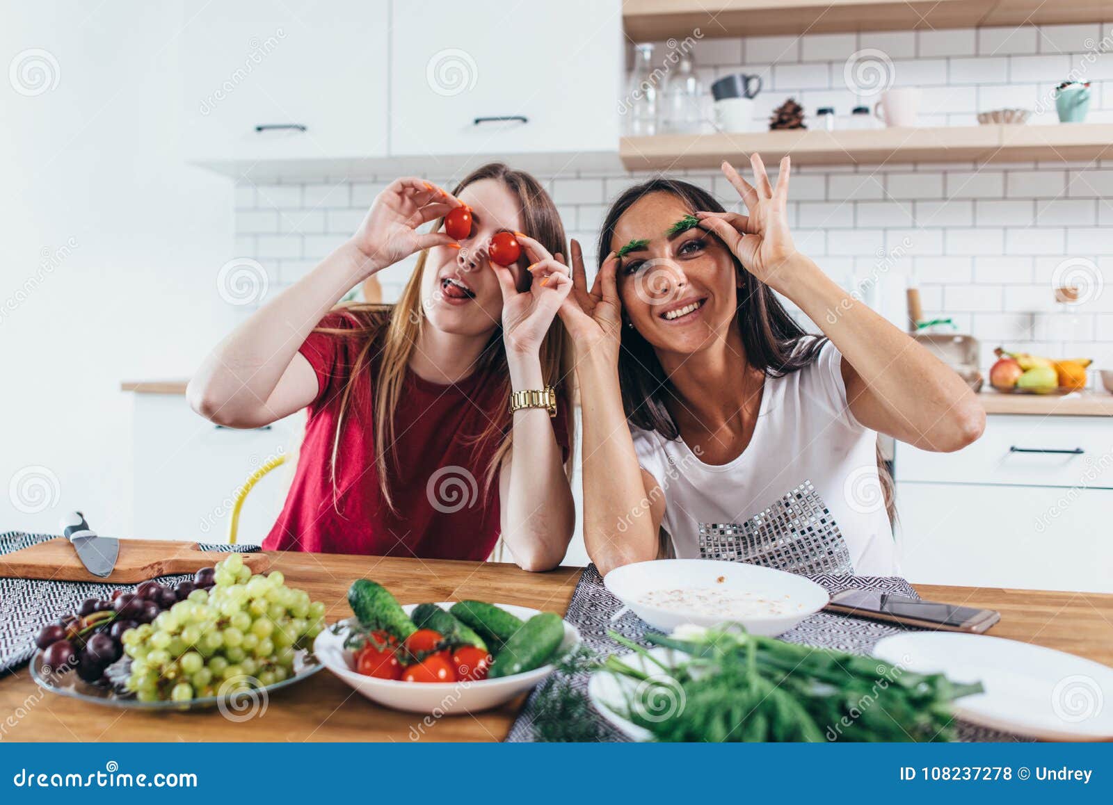 Girls Fooling Around In The Kitchen Playing With Vegetables Stock