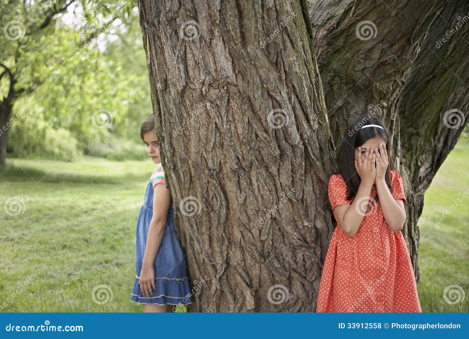 Girls Playing Hide and Seek by Tree Stock Photo - Image of person ...