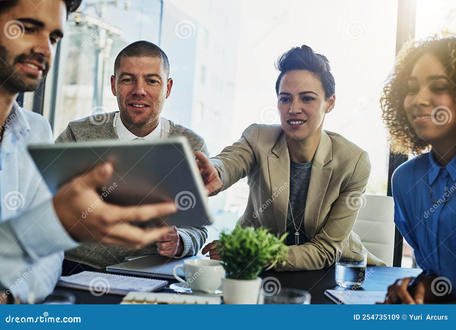 Giving Her Input. a Group of Colleagues Using a Tablet while Meeting in ...