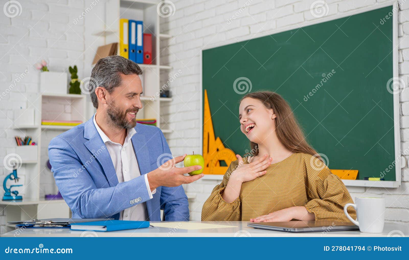 Glad Child in Classroom with Tutor Sharing Apple Stock Photo - Image of ...
