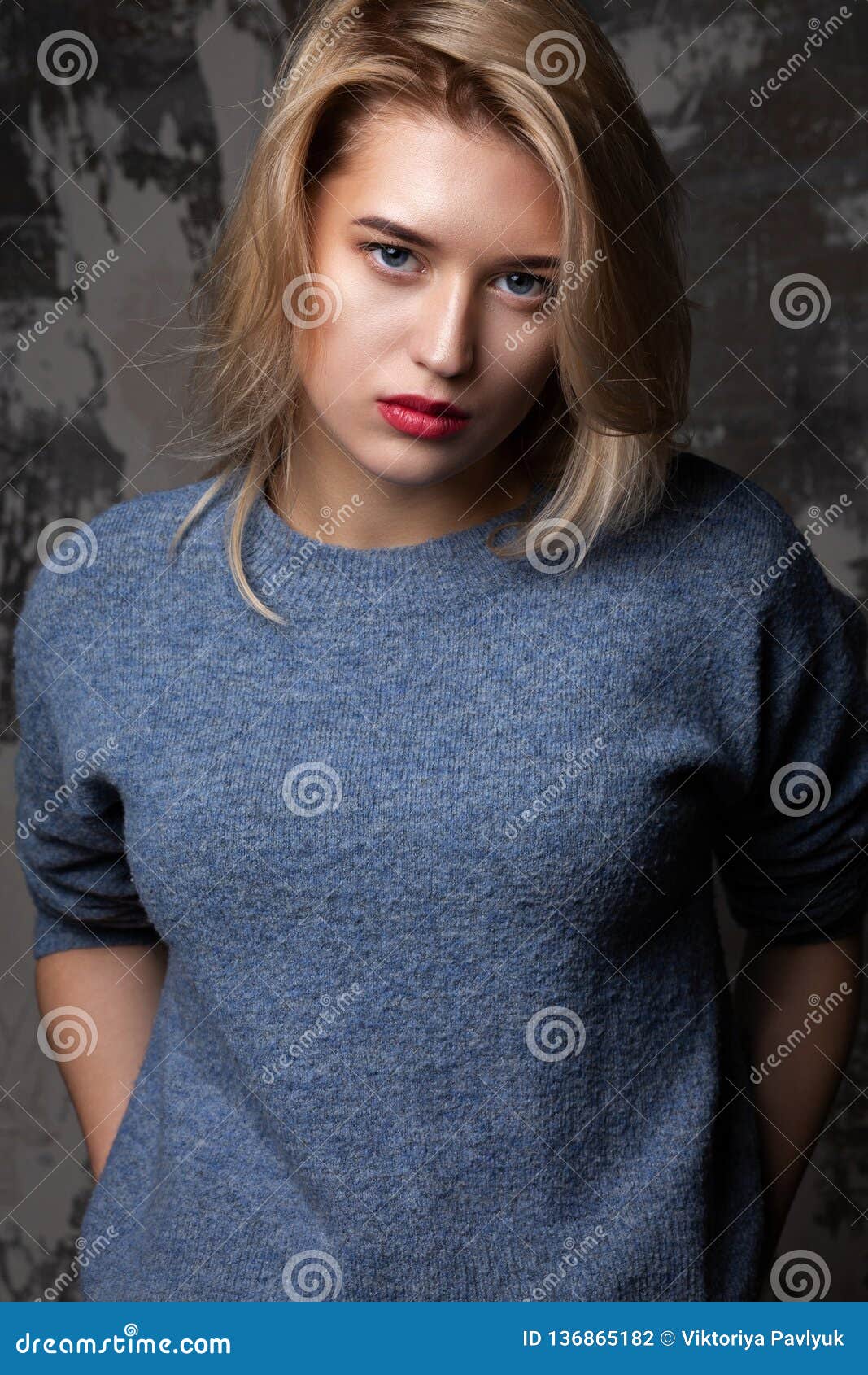 Glamor Blonde Model With Lush Hair Wearing Blue Sweater Posing In