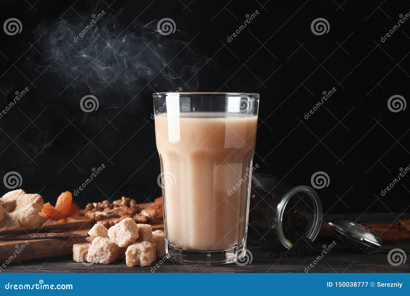 Glass of Aromatic Tea with Milk on Table Against Dark Background Stock ...