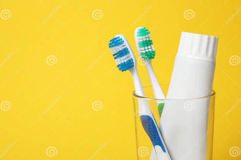 Glass with Brushes and Toothpaste on Color Background Stock Image ...