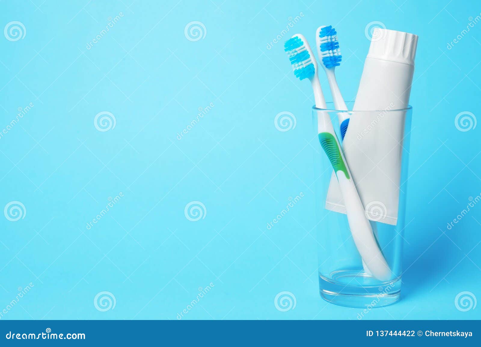 Glass with Brushes and Toothpaste on Color Background Stock Photo ...