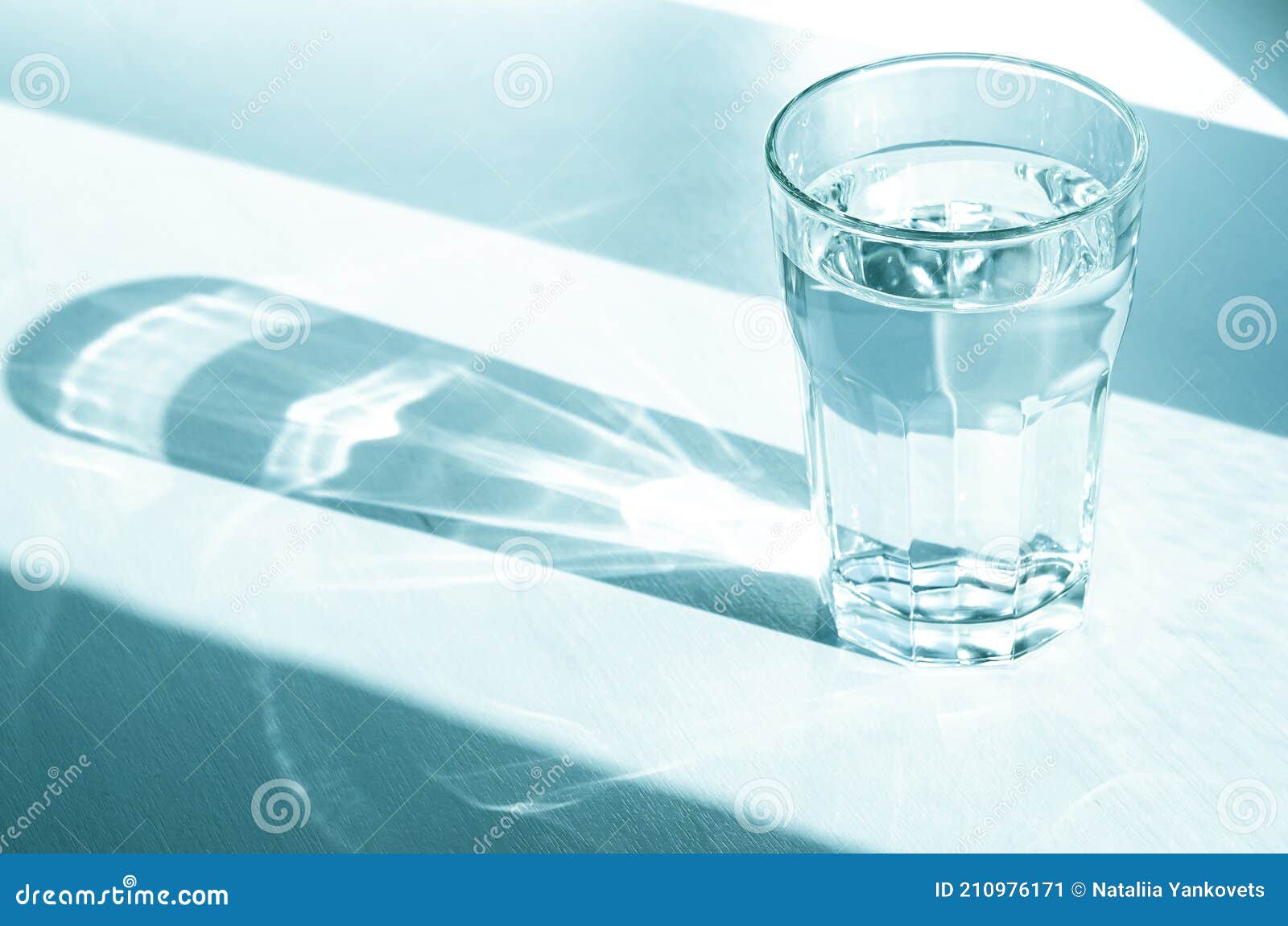 A Glass with Clean Clear Water and Sharp Shadows Stands on a White ...